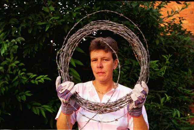 Lady holding up a roll of barbed wire - Living Archive